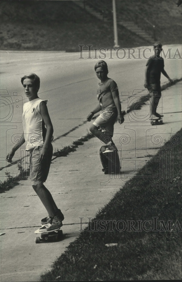 1988 Press Photo Three skateboarders rolling down main street Milwauke - Historic Images