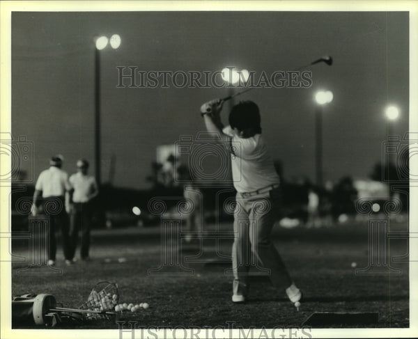 Press Photo Golfer practices his drive under lights at Houston driving ...