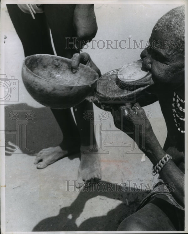1956 Press Photo Toothless woman drinks water by pouring liquid onto ...