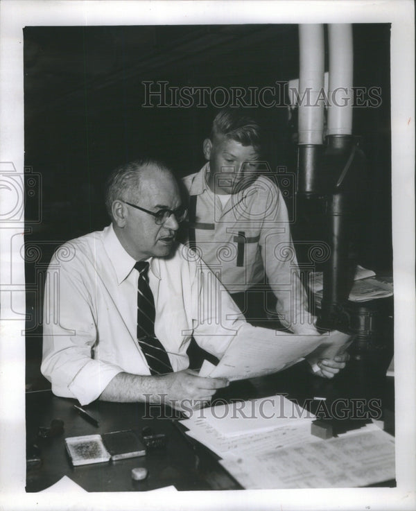 1954 Merritt Johnson, copy desk chief, explains work to a young man ...
