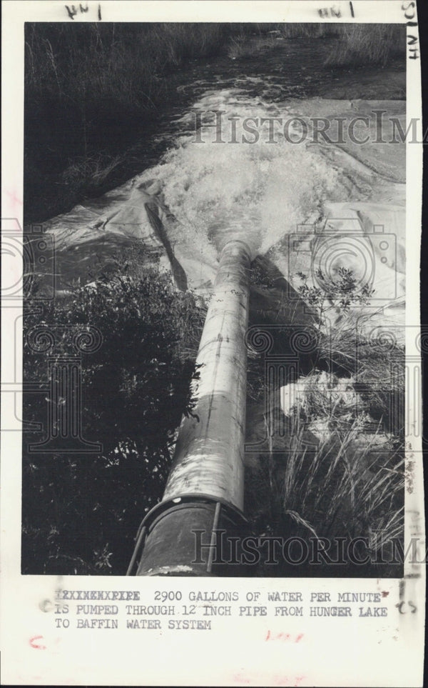 1980 Water gushing from a pipe from hunger lake to baffin - Historic Images
