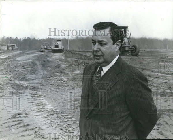 1982, Olin B. King of SCI Systems stands among heavy dirt movers ...