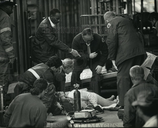 1991 Press Photo Emergency personnel assist Paul Mandella, injured by ...
