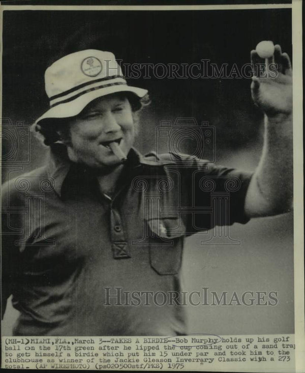 1975 Press Photo Golfer Bob Murphy, with cigar in mouth, holds up his ...